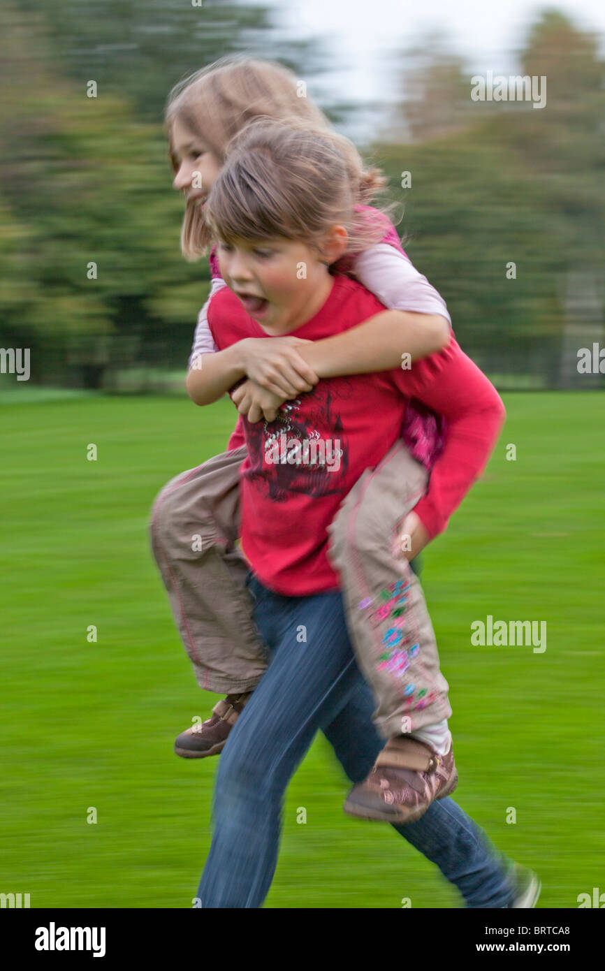 young girl running with her friend piggyback Stock Photo - Alamy
