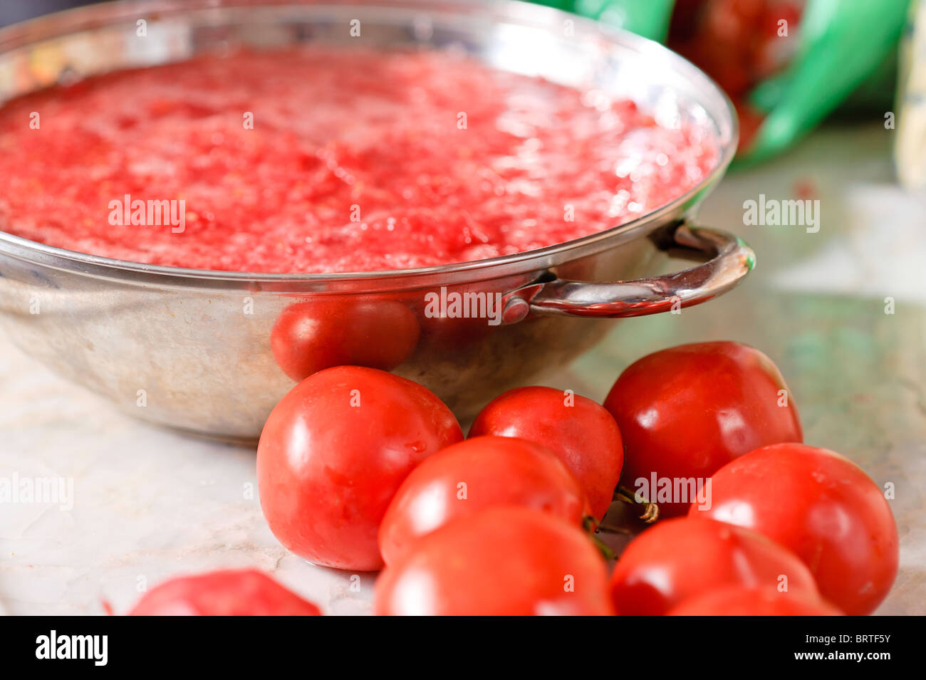 Tomatoes on a sunlight kitchen marble work surface in front of a steel ...