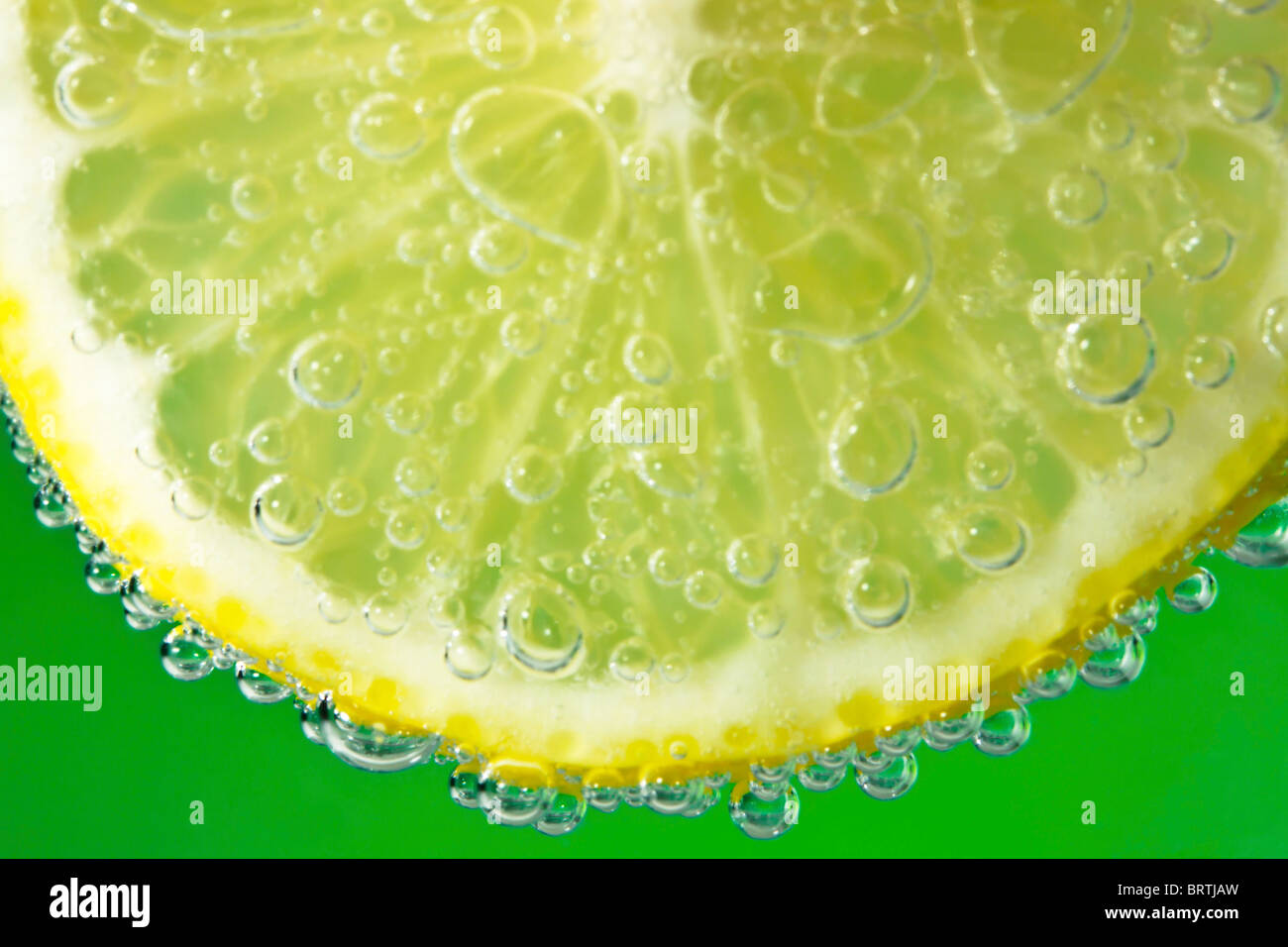 Bubbly lemon slice over green Stock Photo - Alamy