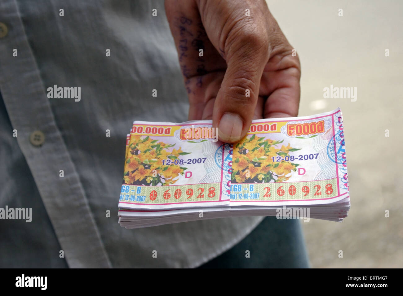 An Asian man is working on a street as a salesman selling lottery ...