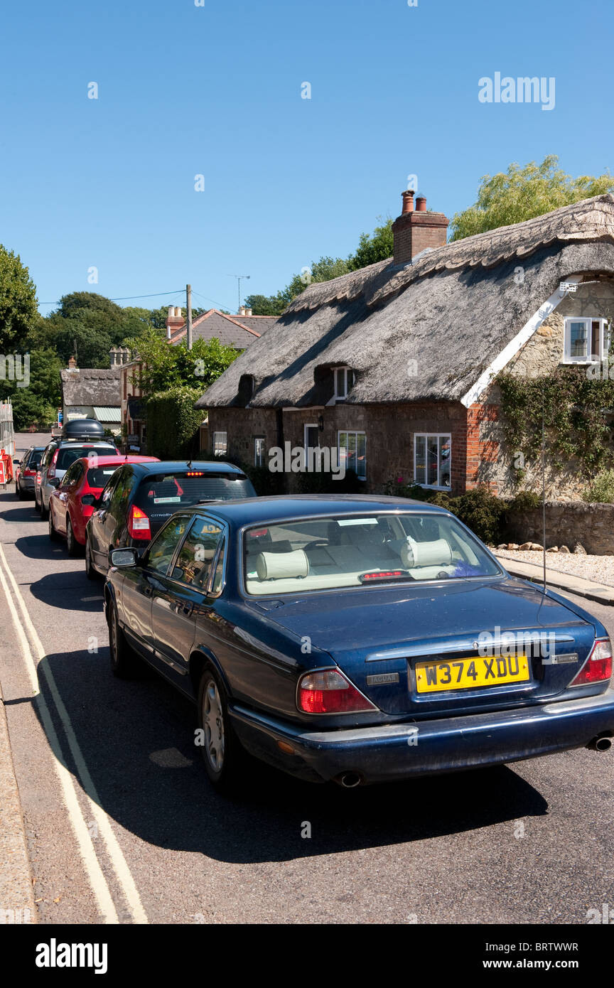 Cars queuing on a road through the pretty village of Godshill on the ...
