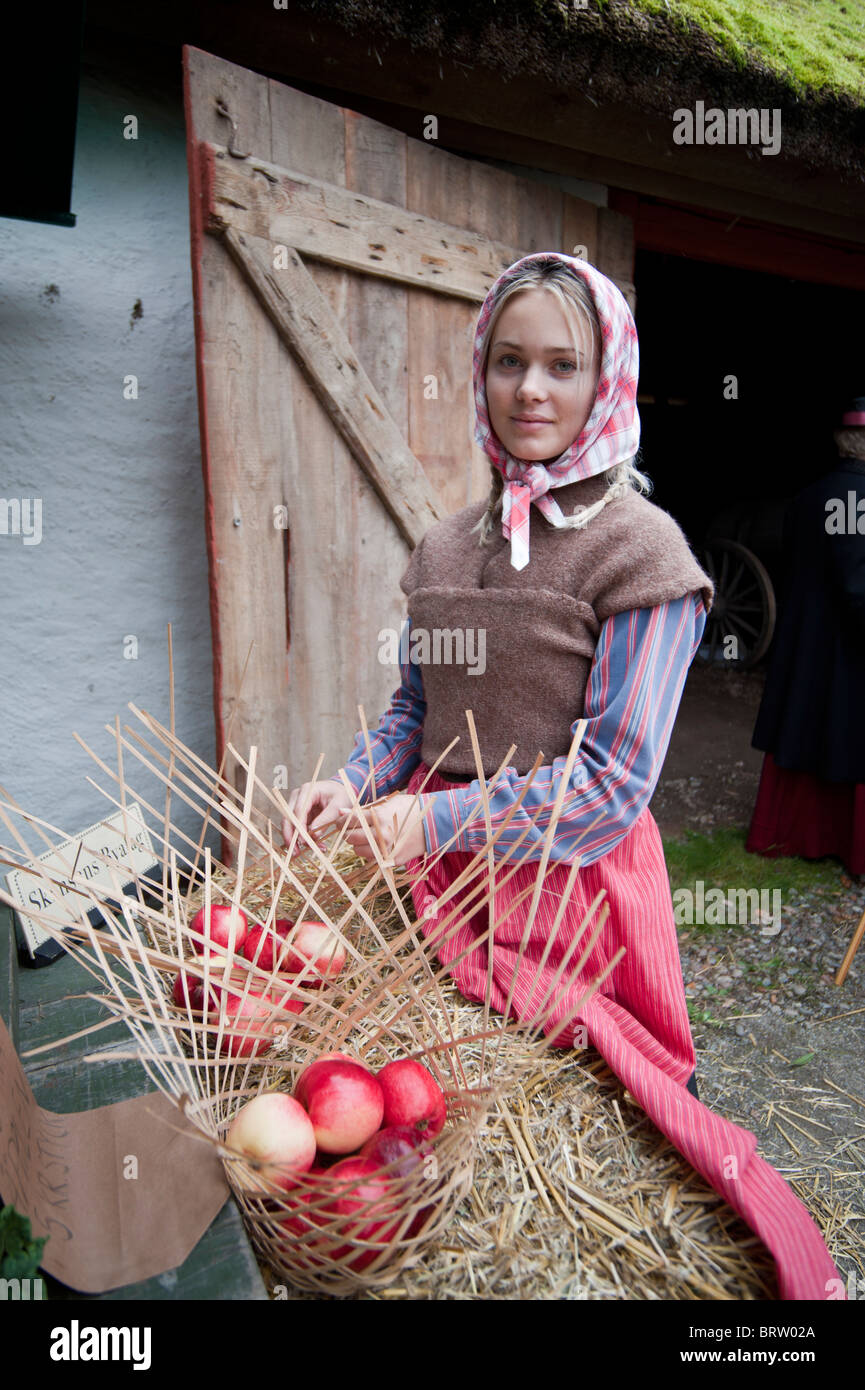 Young girl in traditional sweden rural dress with two baskets of apples ...