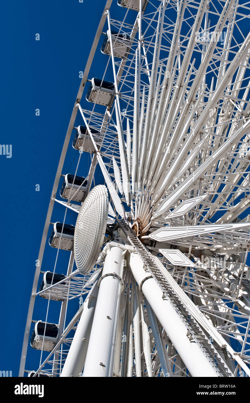 A large white ferris wheel with enclosed cars shot from below with a ...