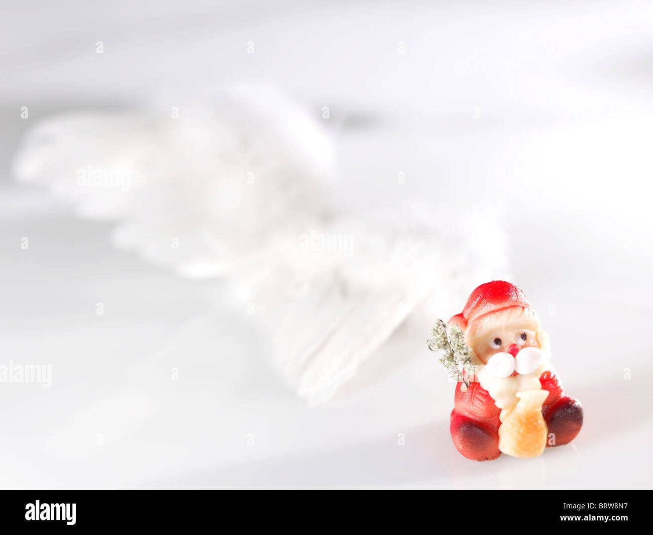 Angels's wings on white surface with a marzipan Santa Stock Photo - Alamy