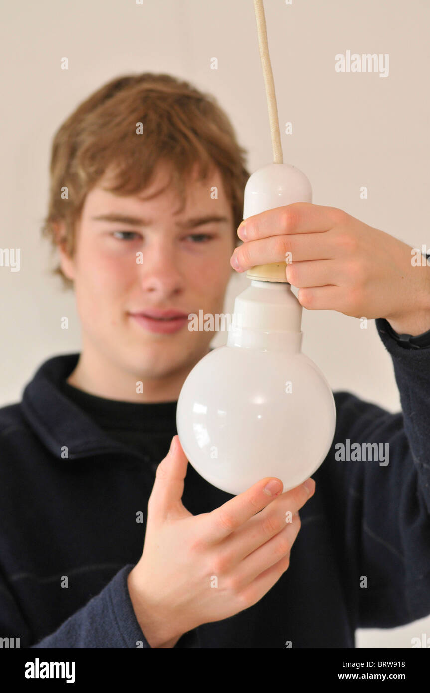 Young man screwing energy saving lamp into a bulbholder Stock Photo - Alamy