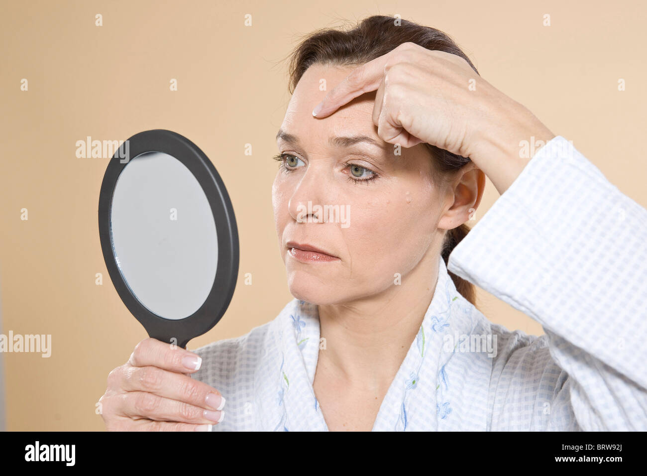 Woman checking her wrinkles with a hand mirror Stock Photo - Alamy