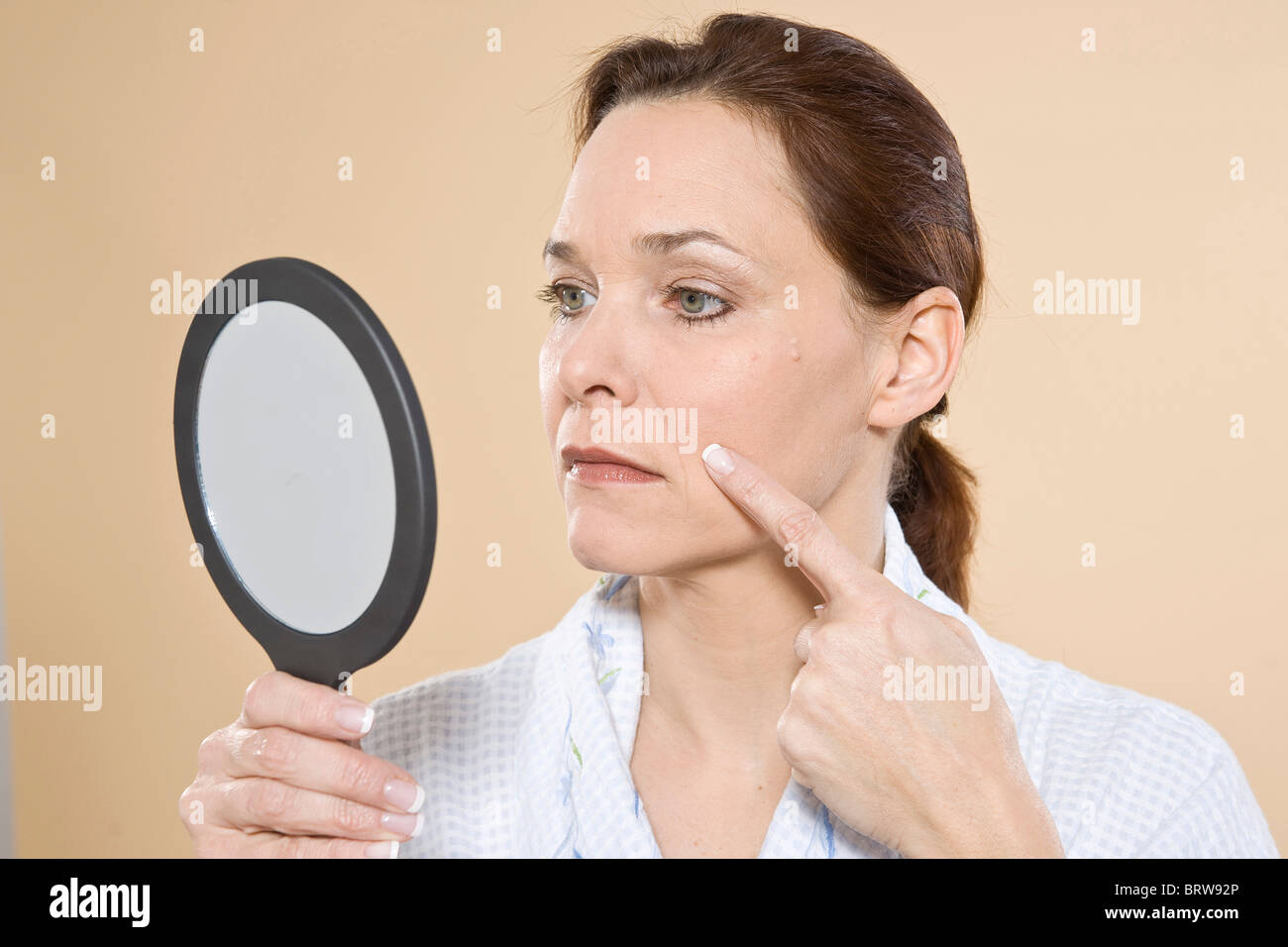 Woman checking her wrinkles with a hand mirror Stock Photo - Alamy
