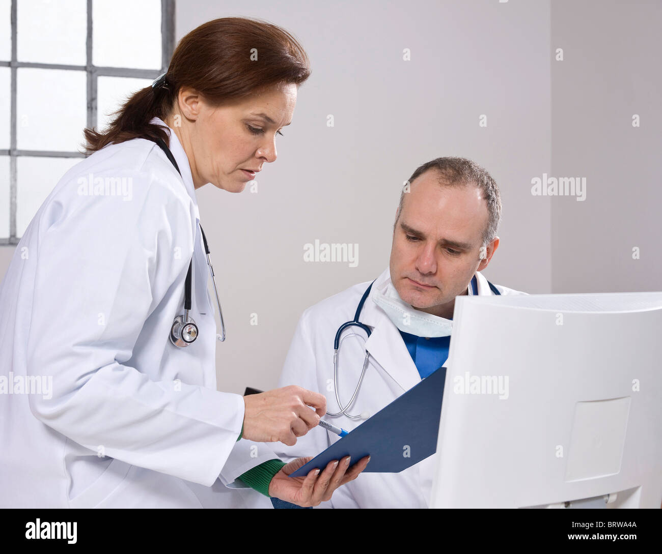 Two doctors talking about diagnostic findings with a file at the ...