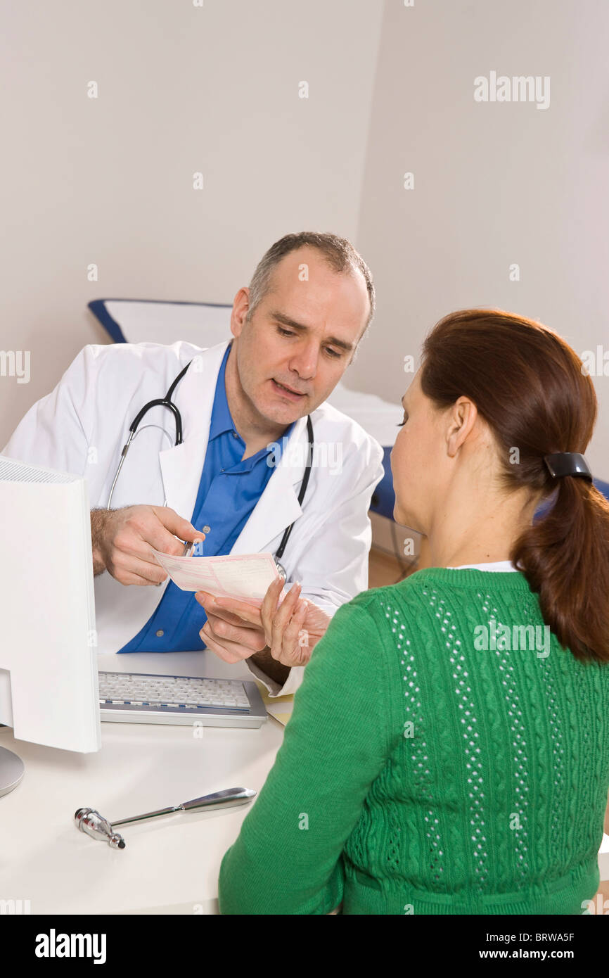 A doctor handing out a prescription to a female patient Stock Photo - Alamy