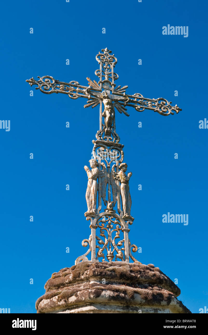 Roadside decorative wrought iron cross on hexagonal carved stone plinth ...