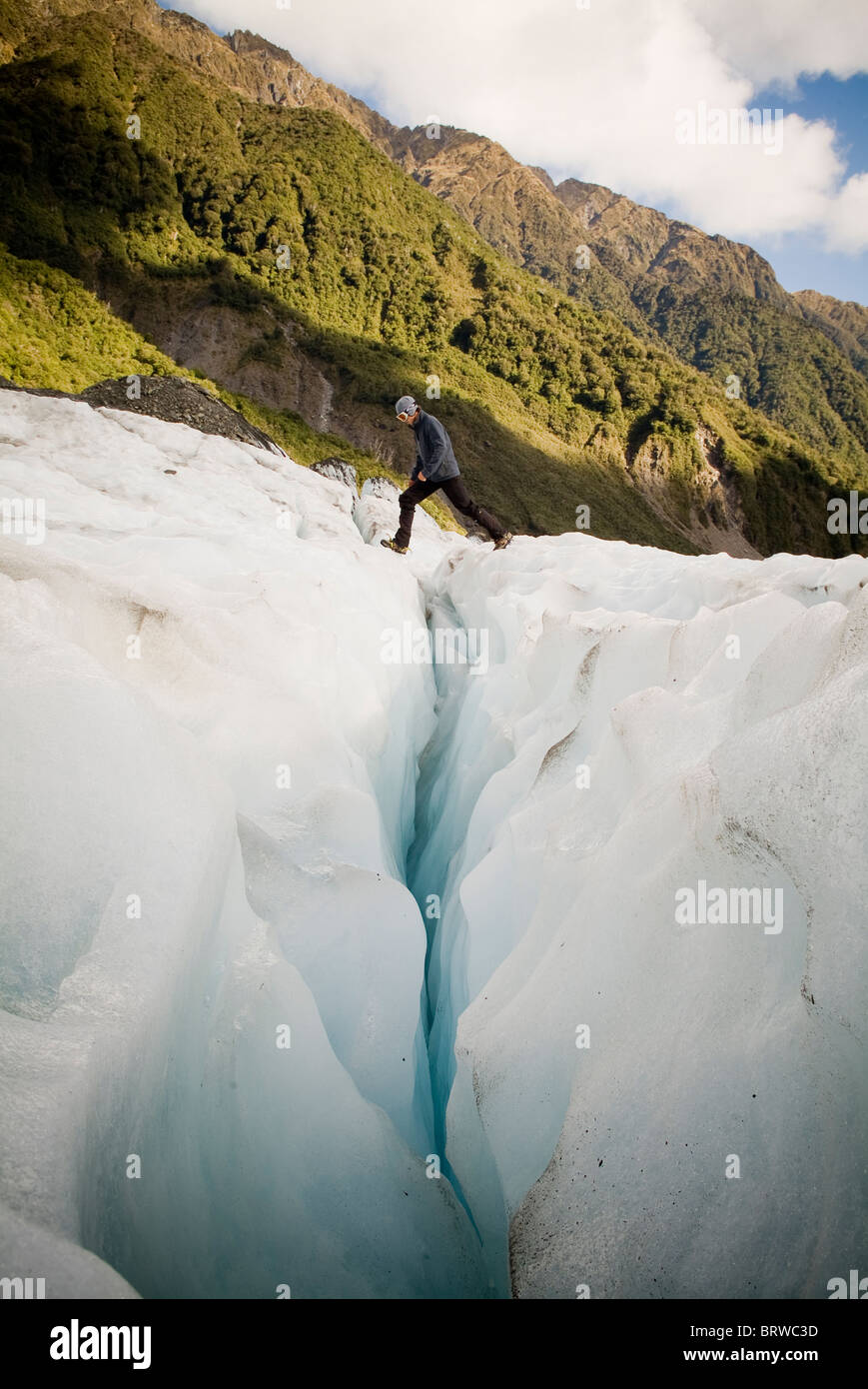 Man crosses a deep crevasse on a glacier Stock Photo - Alamy