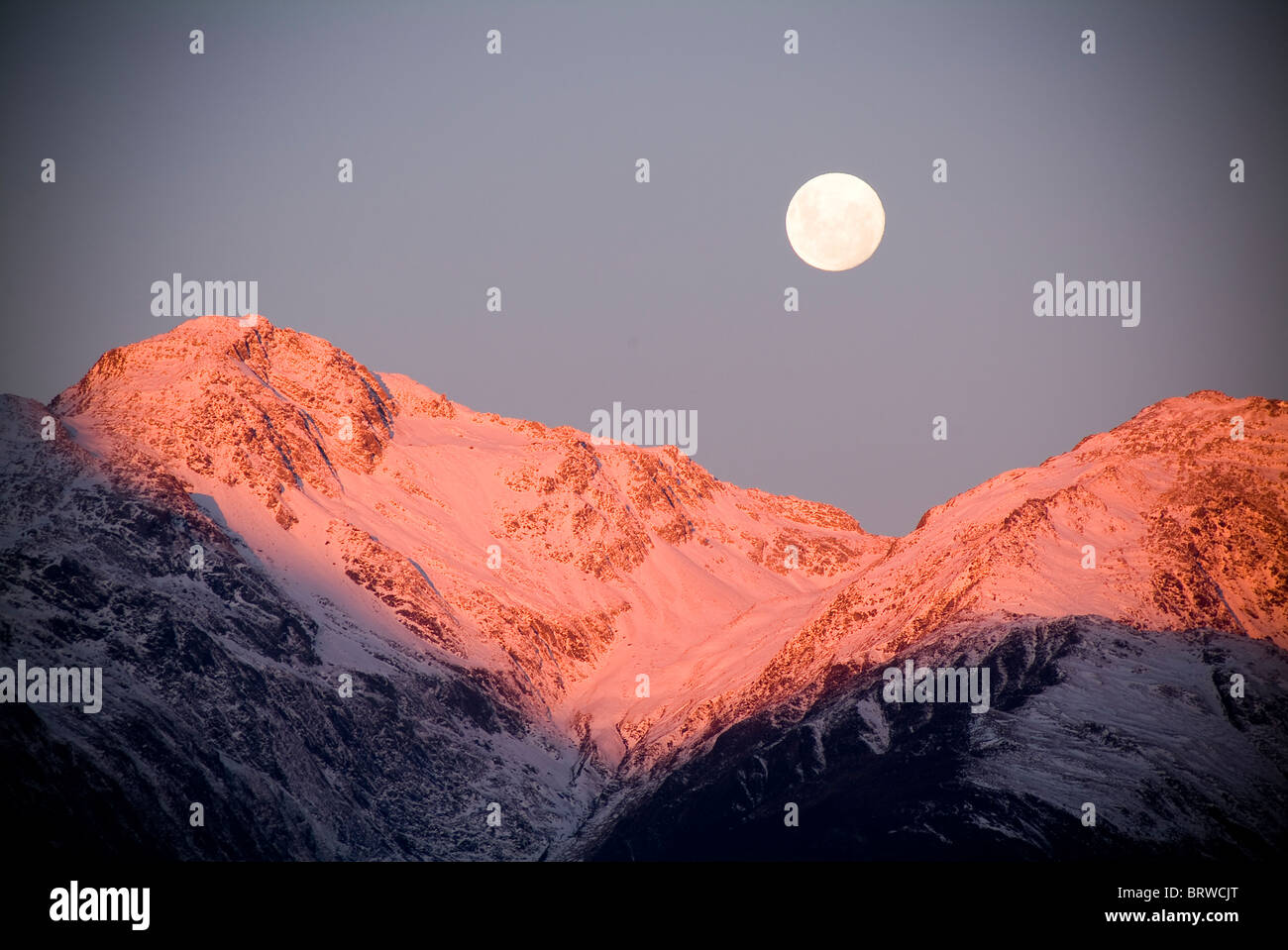 Moon rises over snow capped mountains at twilight Stock Photo - Alamy