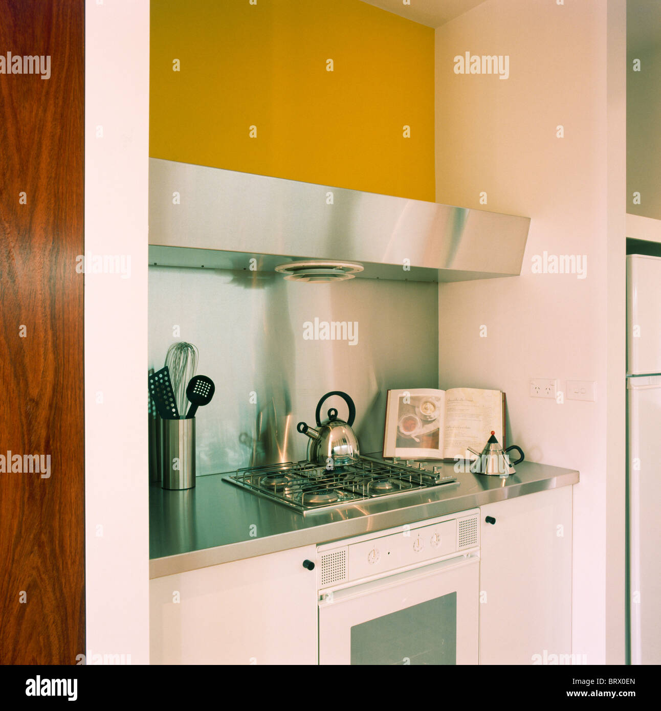 Close-up of stainless-steel kettle on hob in recessed fitted unit with ...