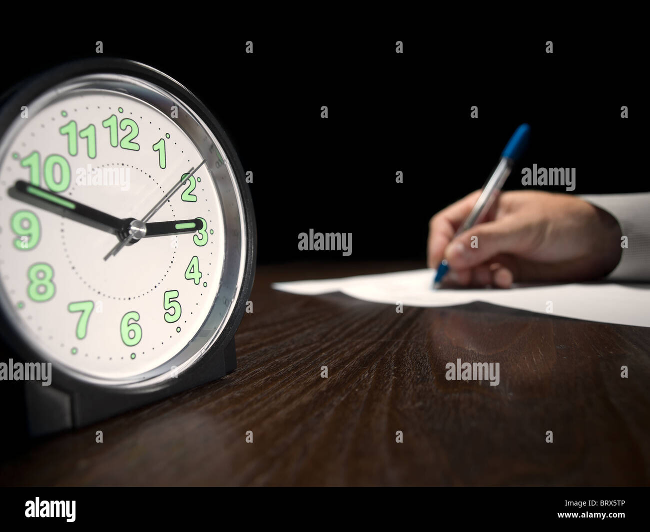 clock with a man doing written test in the background,useful for job ...