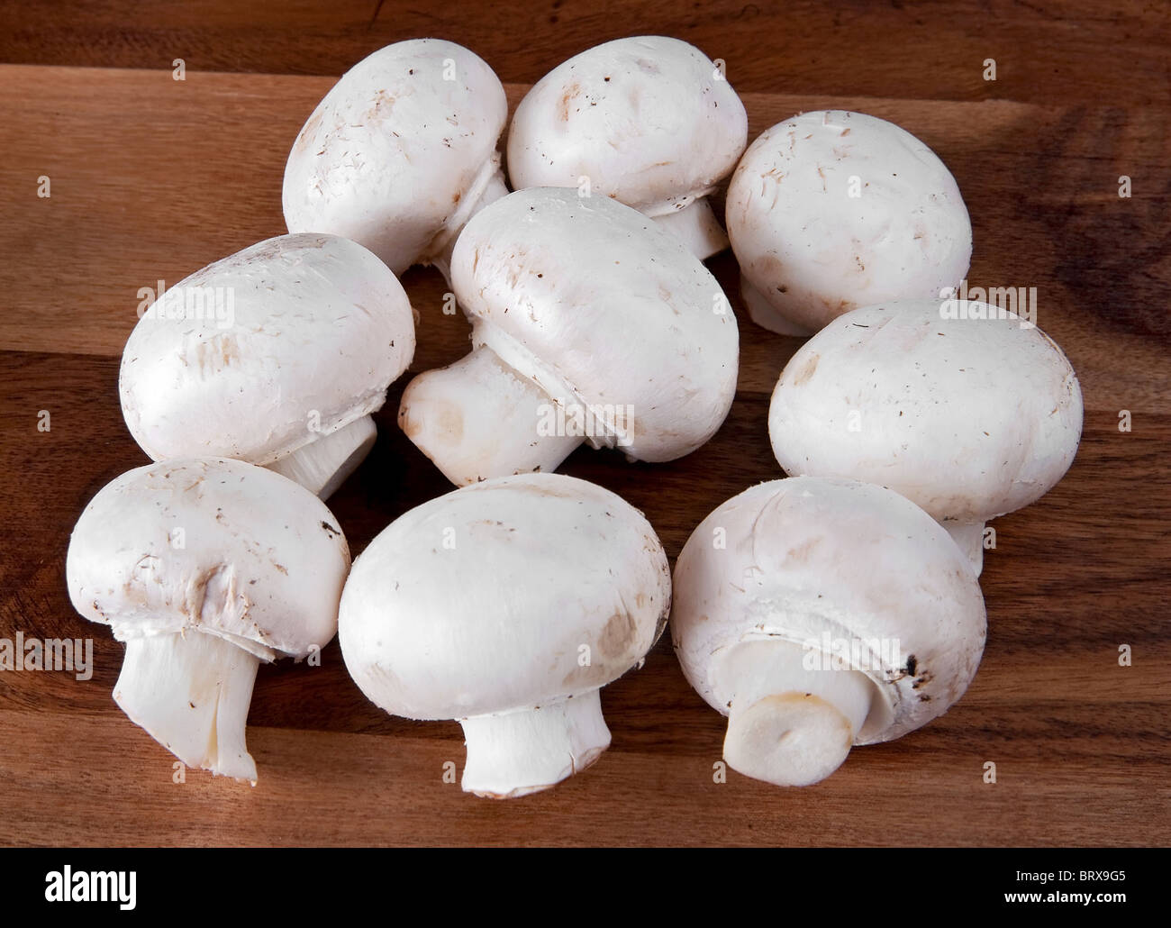 small stack of white button mushrooms on a wooden cutting board Stock ...