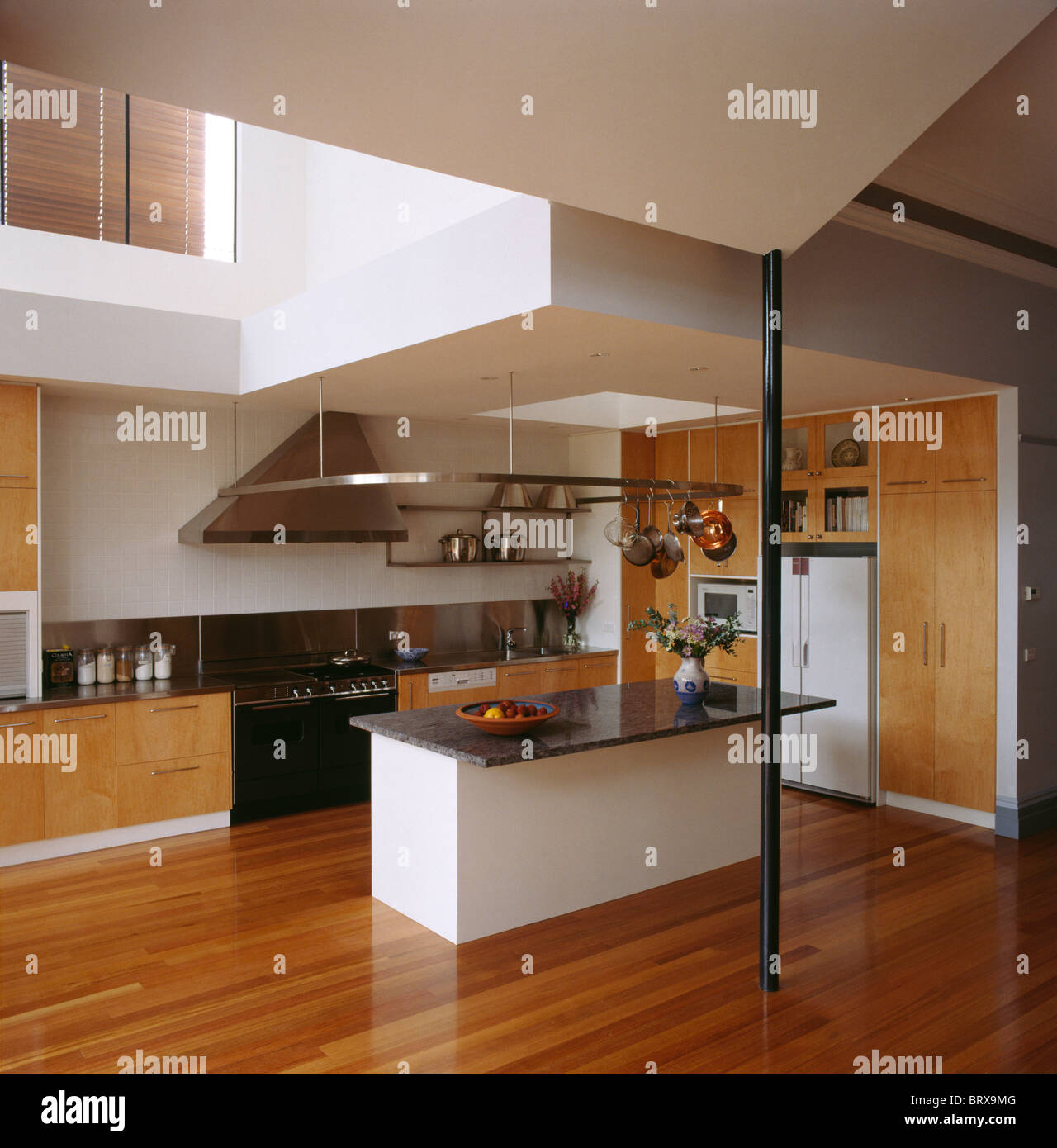 Large modern white kitchen with wooden flooring and granite-topped ...