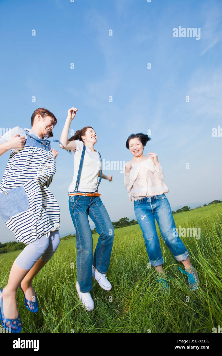 Three Women Jumping in Grass Stock Photo - Alamy