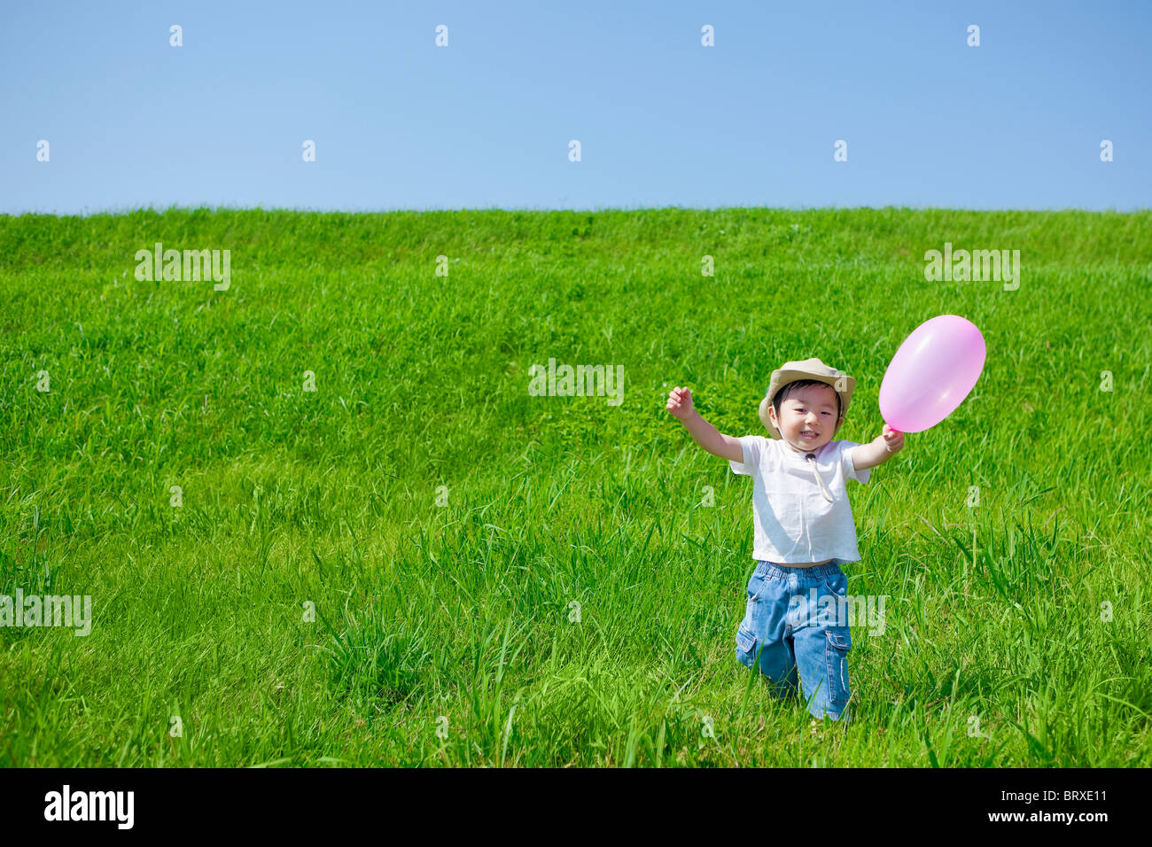 Young Boy Running With Balloon in Field Stock Photo - Alamy