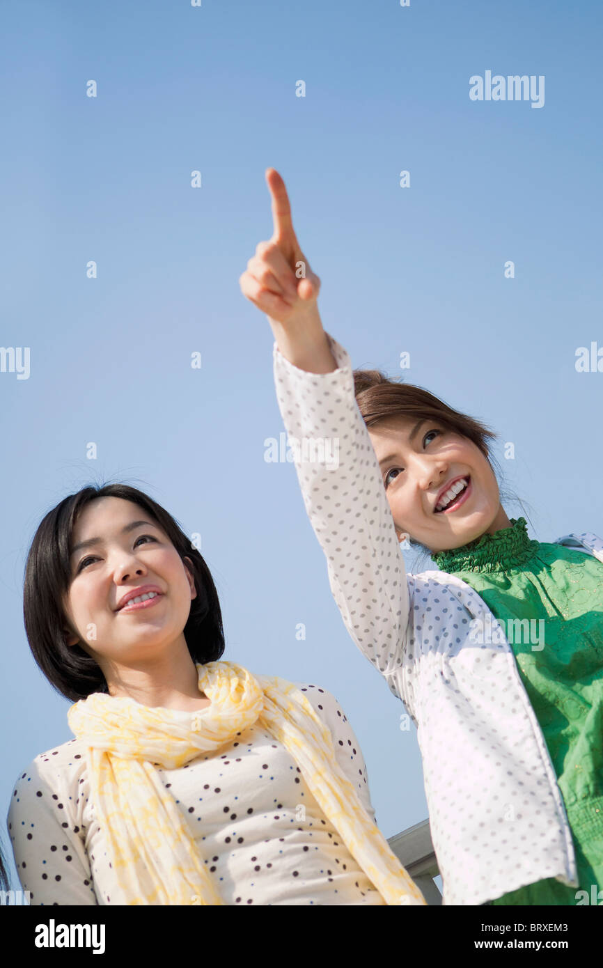 Young Woman Pointing Something to her Friend Stock Photo - Alamy