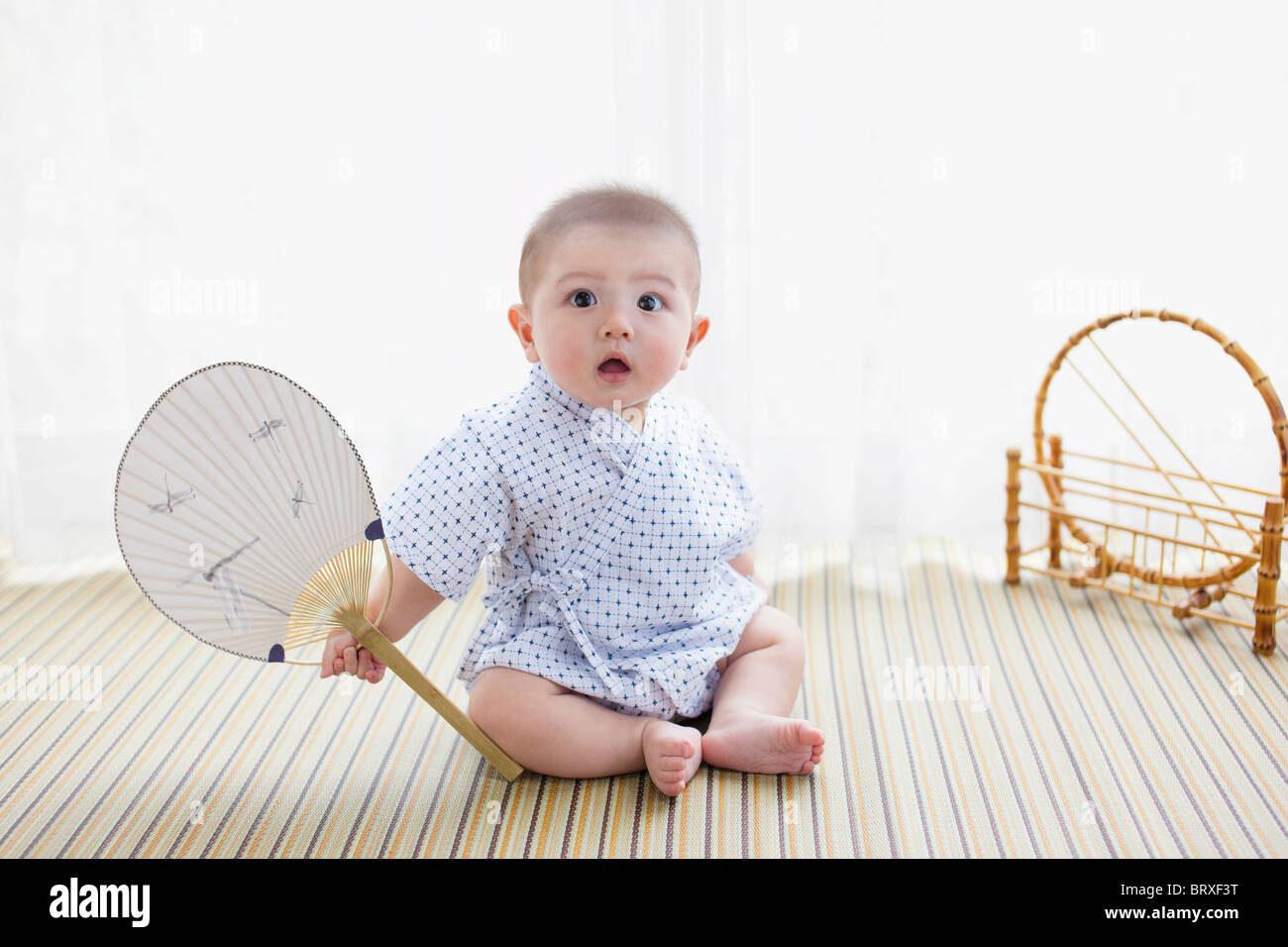 Baby Boy Holding Fan and Looking Surprised Stock Photo - Alamy