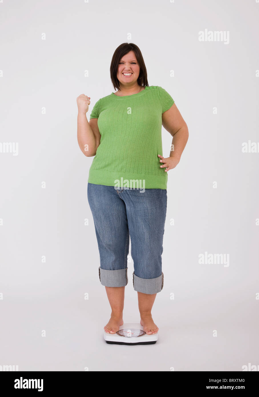 Portrait of young overweight woman standing on scales and cheering ...