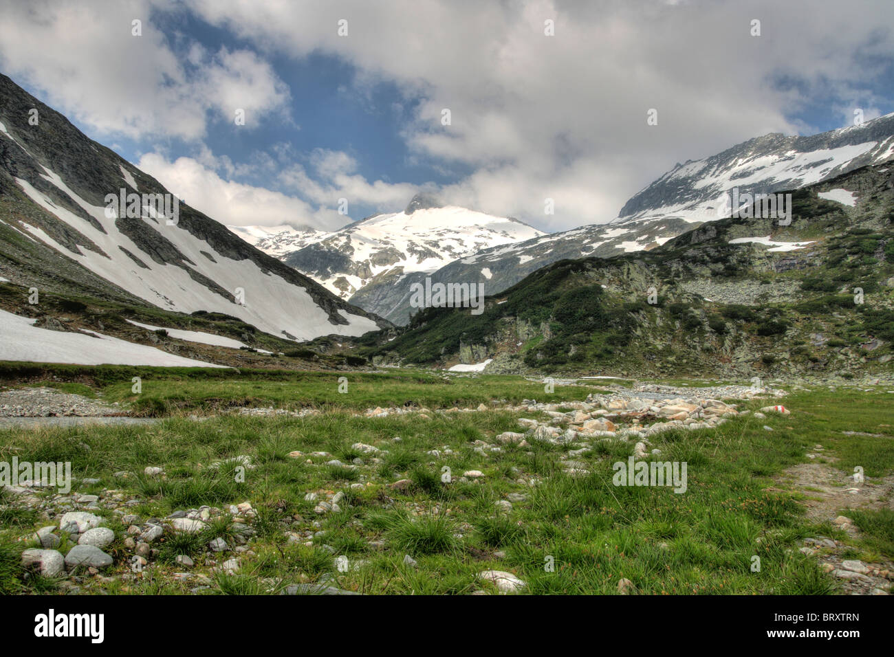 View of alps mountains with snow and dam under high mountain pasture ...