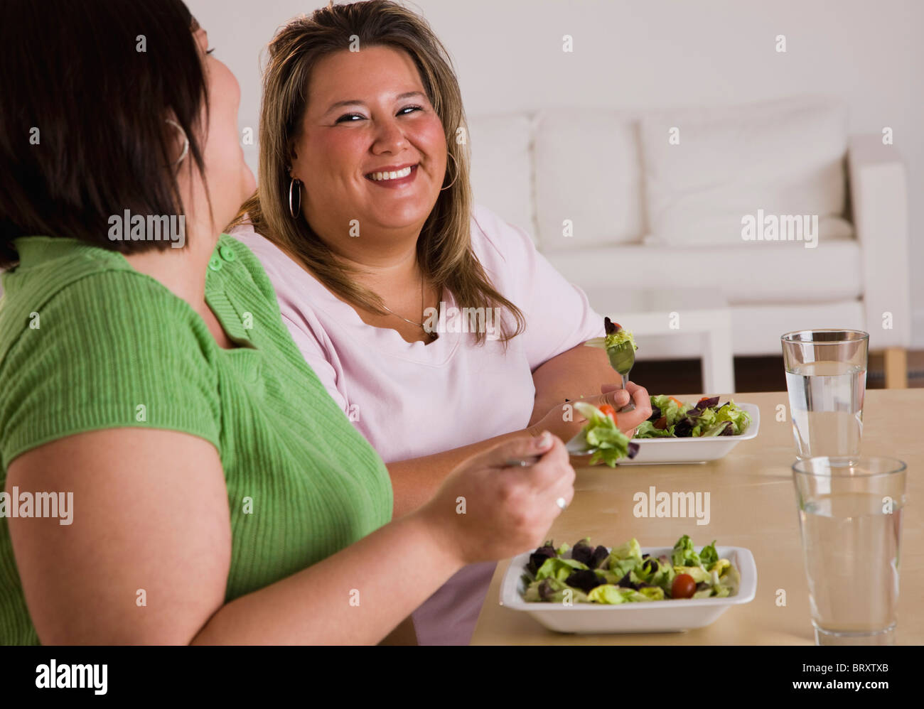 Two women eating salads and laughing Stock Photo - Alamy