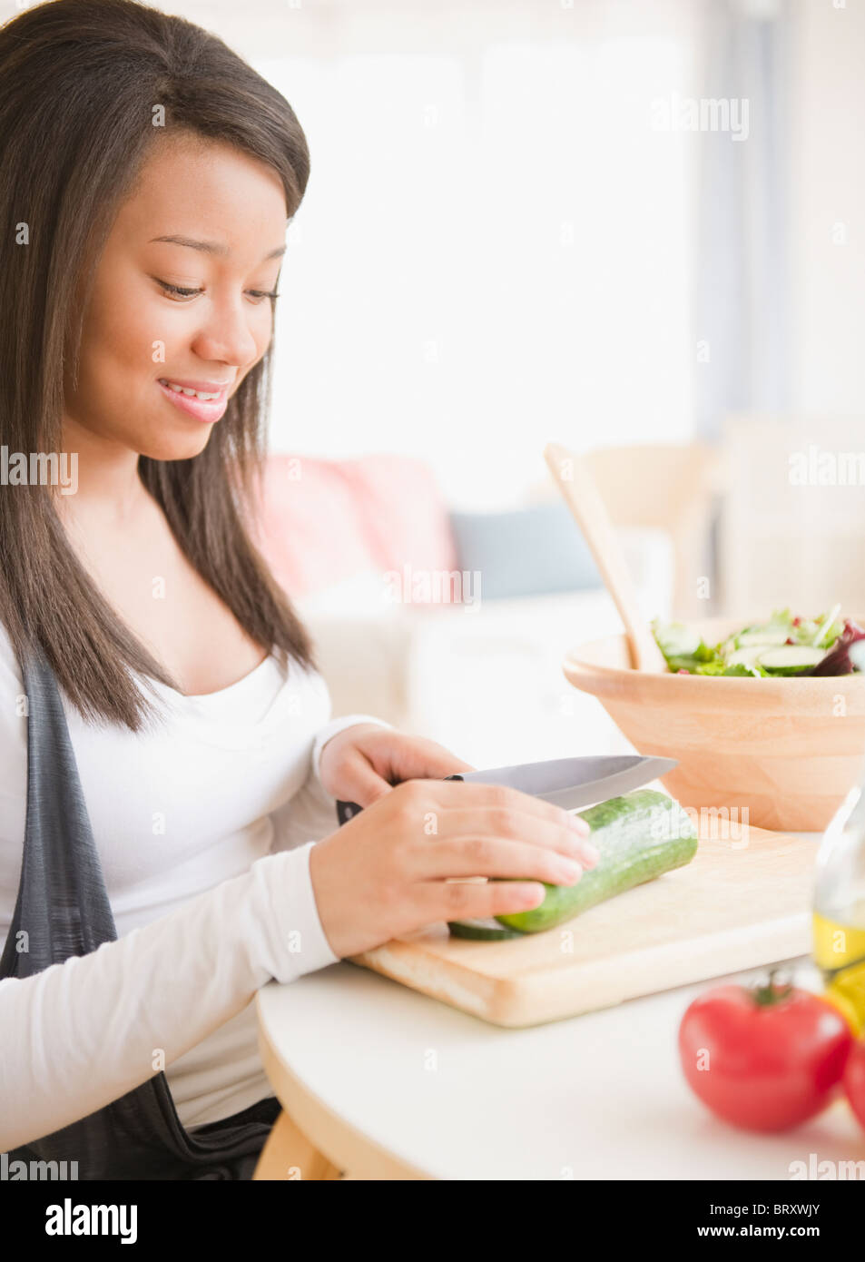 Smiling mixed race teenage girl cutting vegetables Stock Photo - Alamy