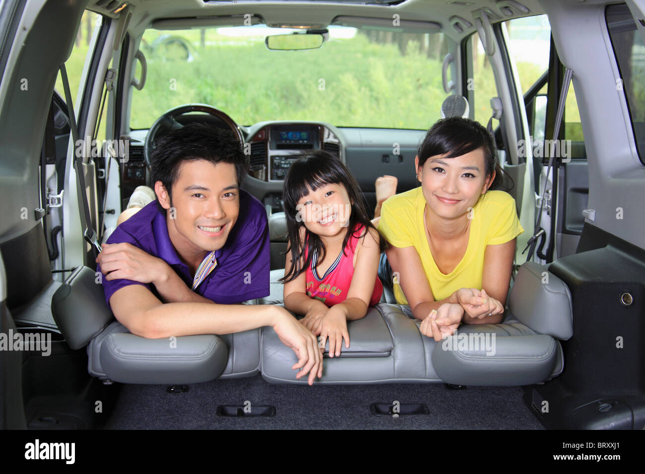 Girl lying in car with her parents smiling Stock Photo - Alamy