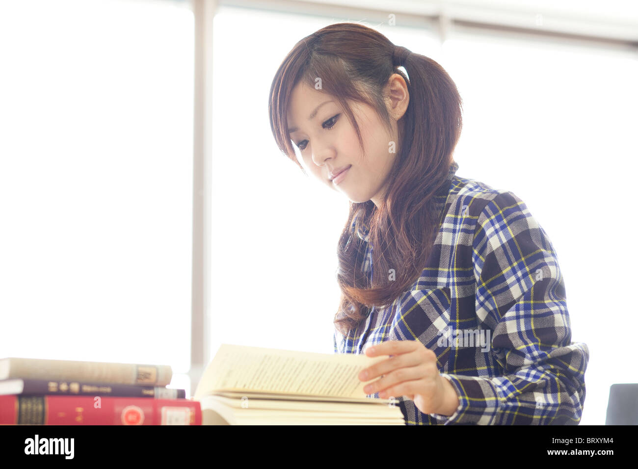 Young woman reading a book in a library Japan Stock Photo - Alamy