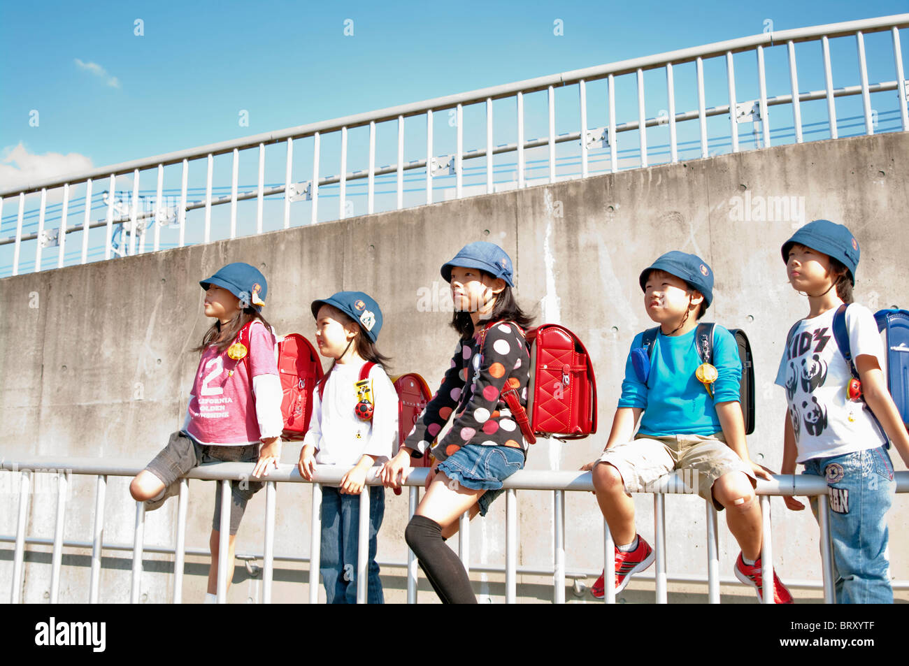 Kids sitting on fence Japan Stock Photo - Alamy
