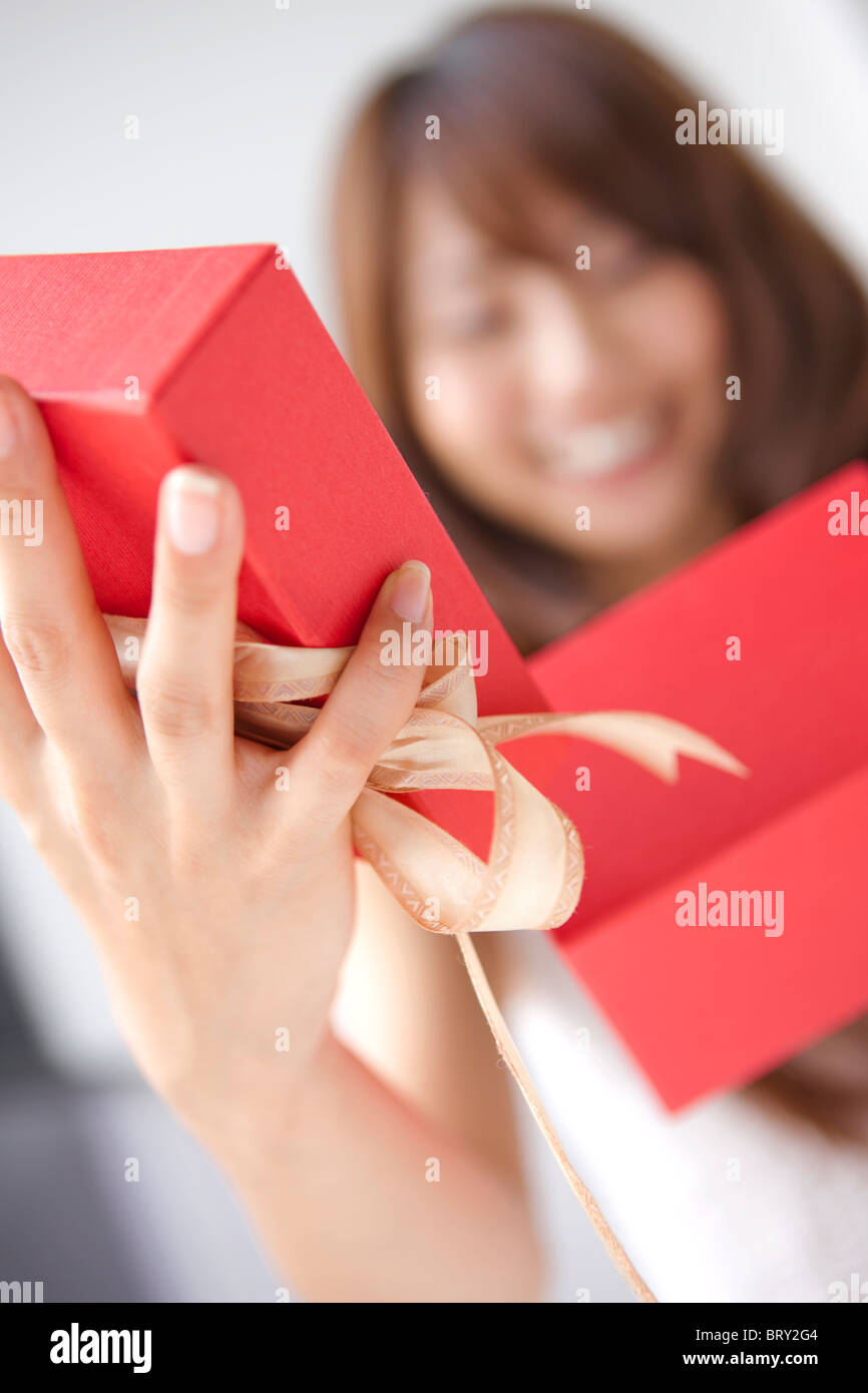 Young woman opening present box, close up, white background ...