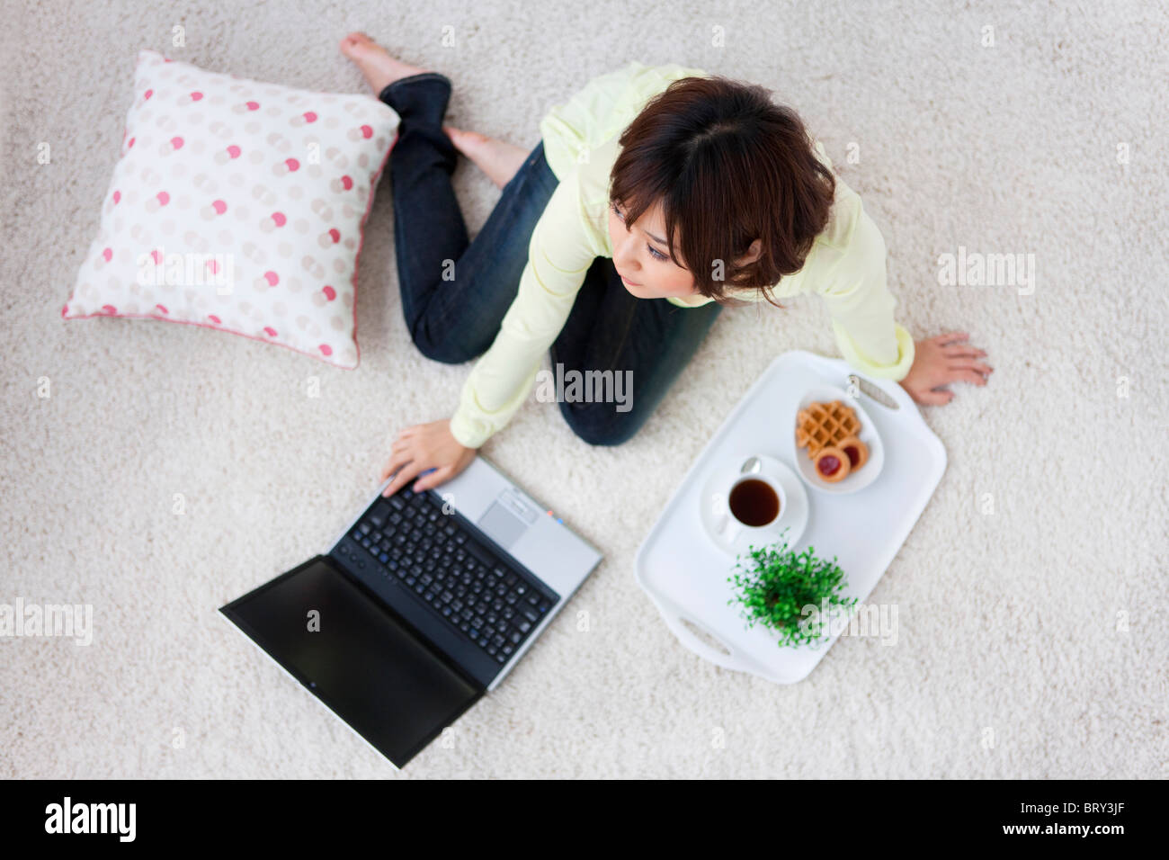 Young woman sitting on carpet, using laptop Stock Photo - Alamy