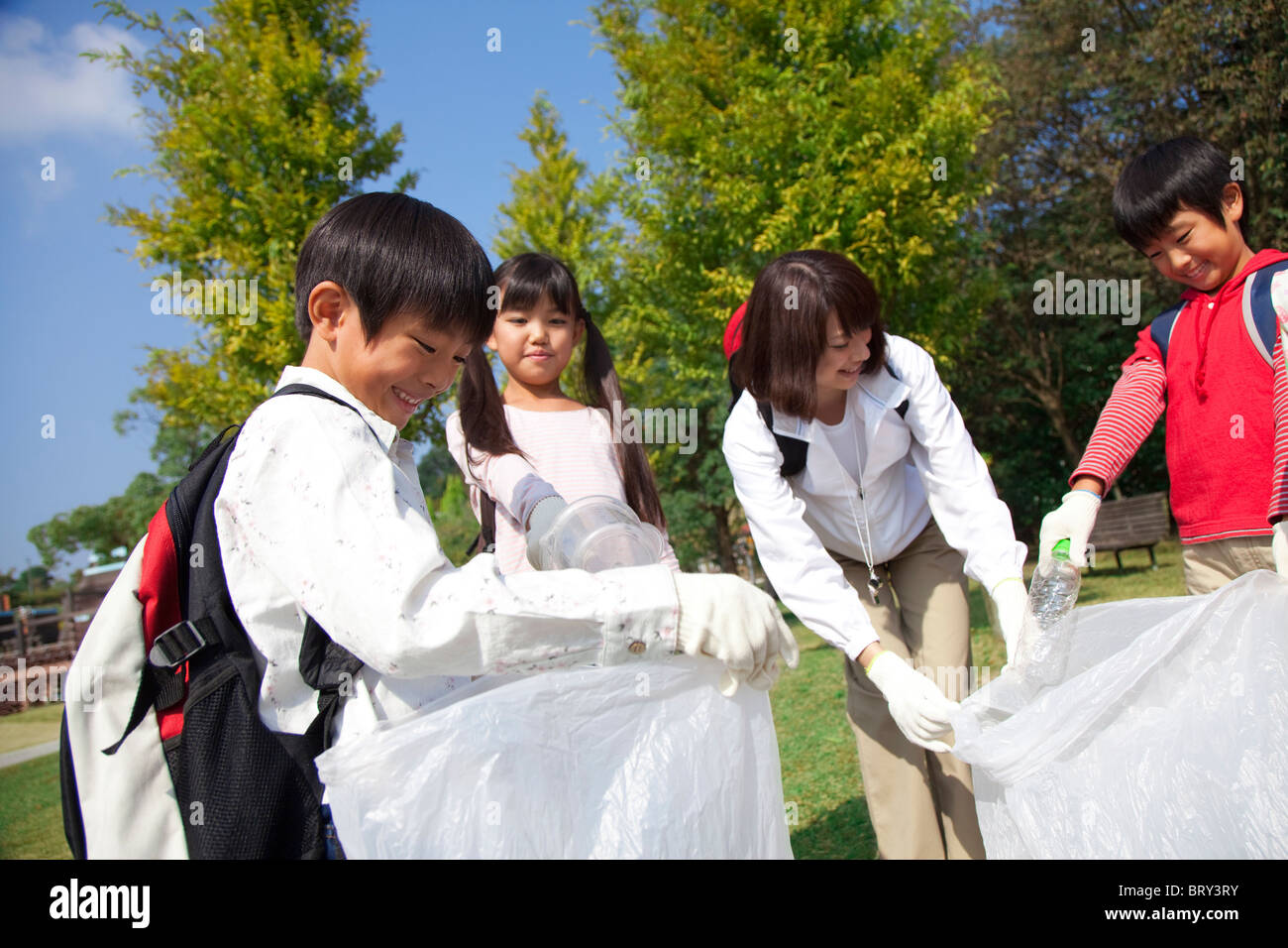 School children with female teacher picking garbage in park Stock Photo ...