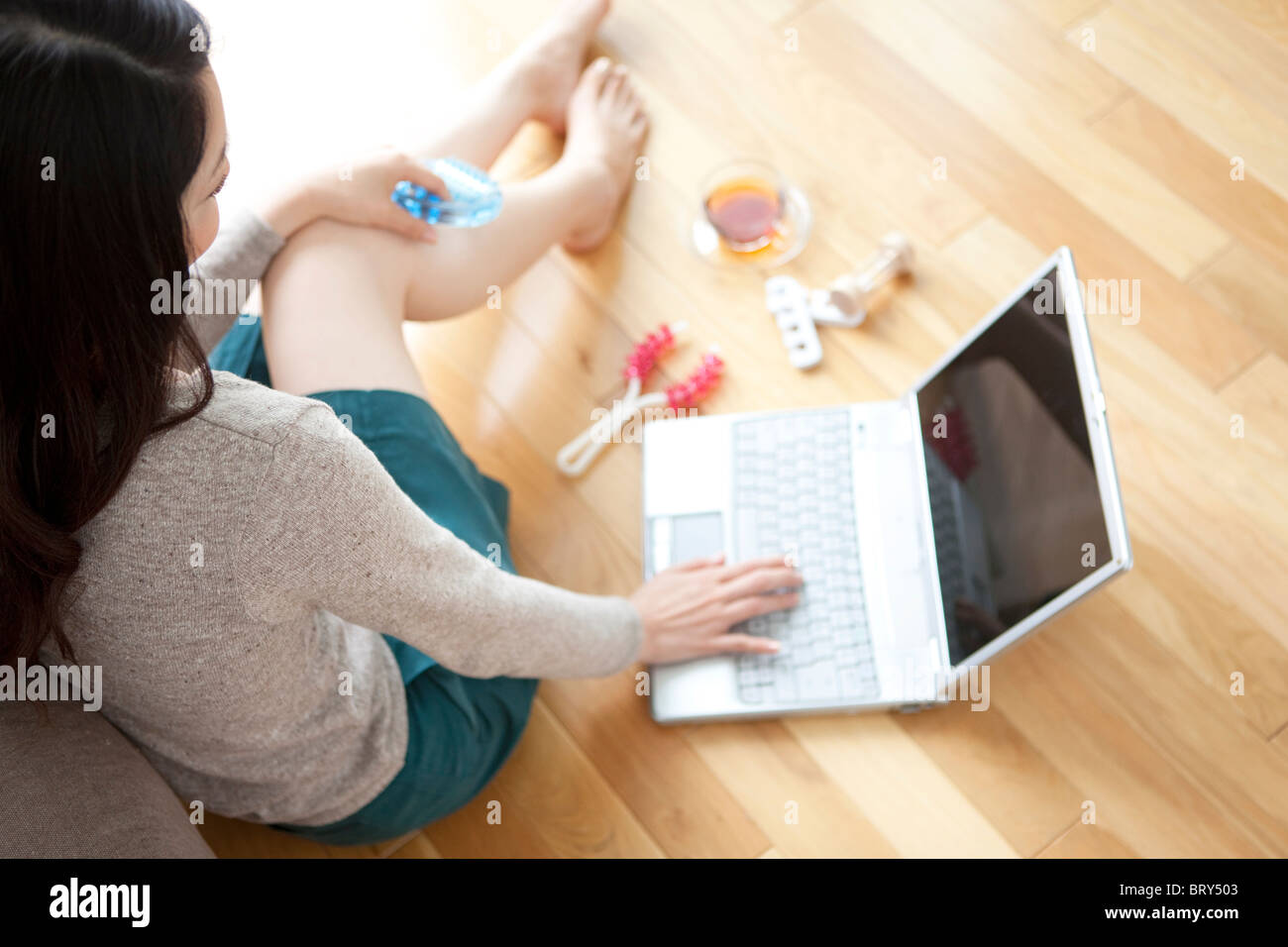 Young woman sitting of floor, using laptop Stock Photo - Alamy