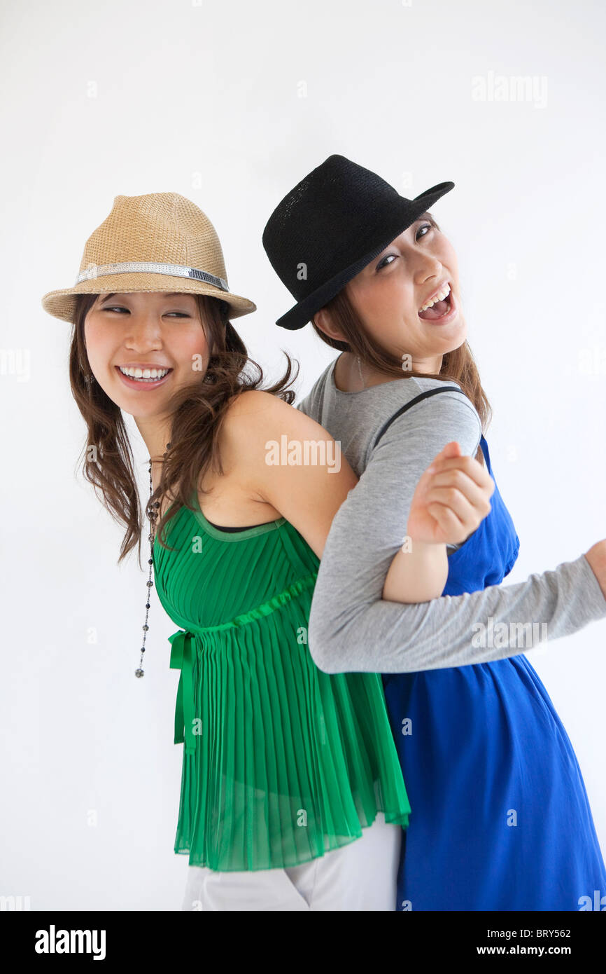 Two young women back to back, smiling, white background Stock Photo - Alamy