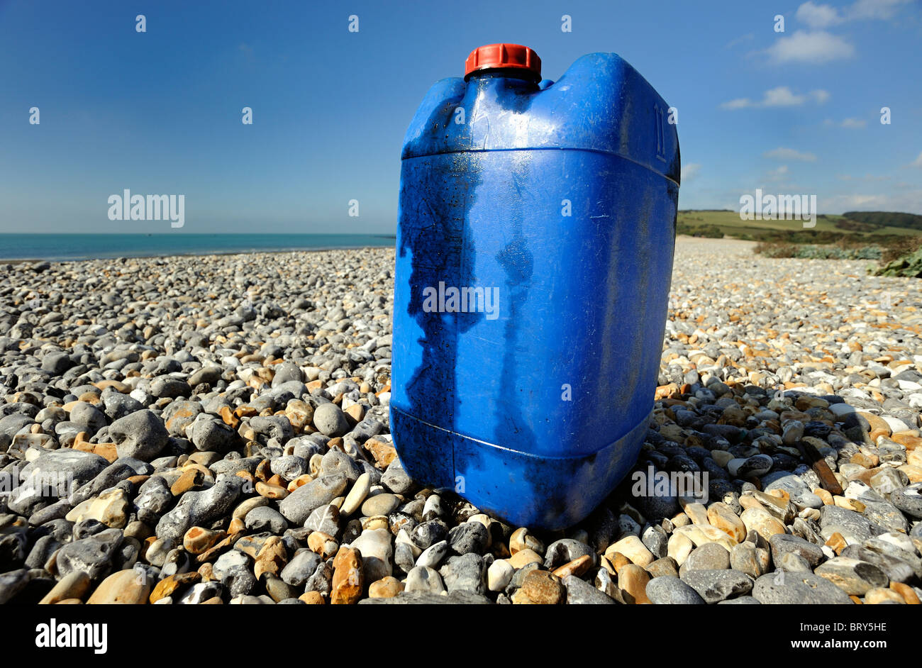 A plastic container of oil leaking and polluting a remote pebble beach ...