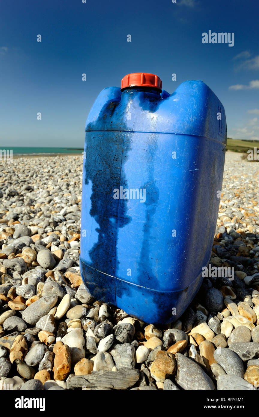 A plastic container of oil leaking and polluting a remote pebble beach ...