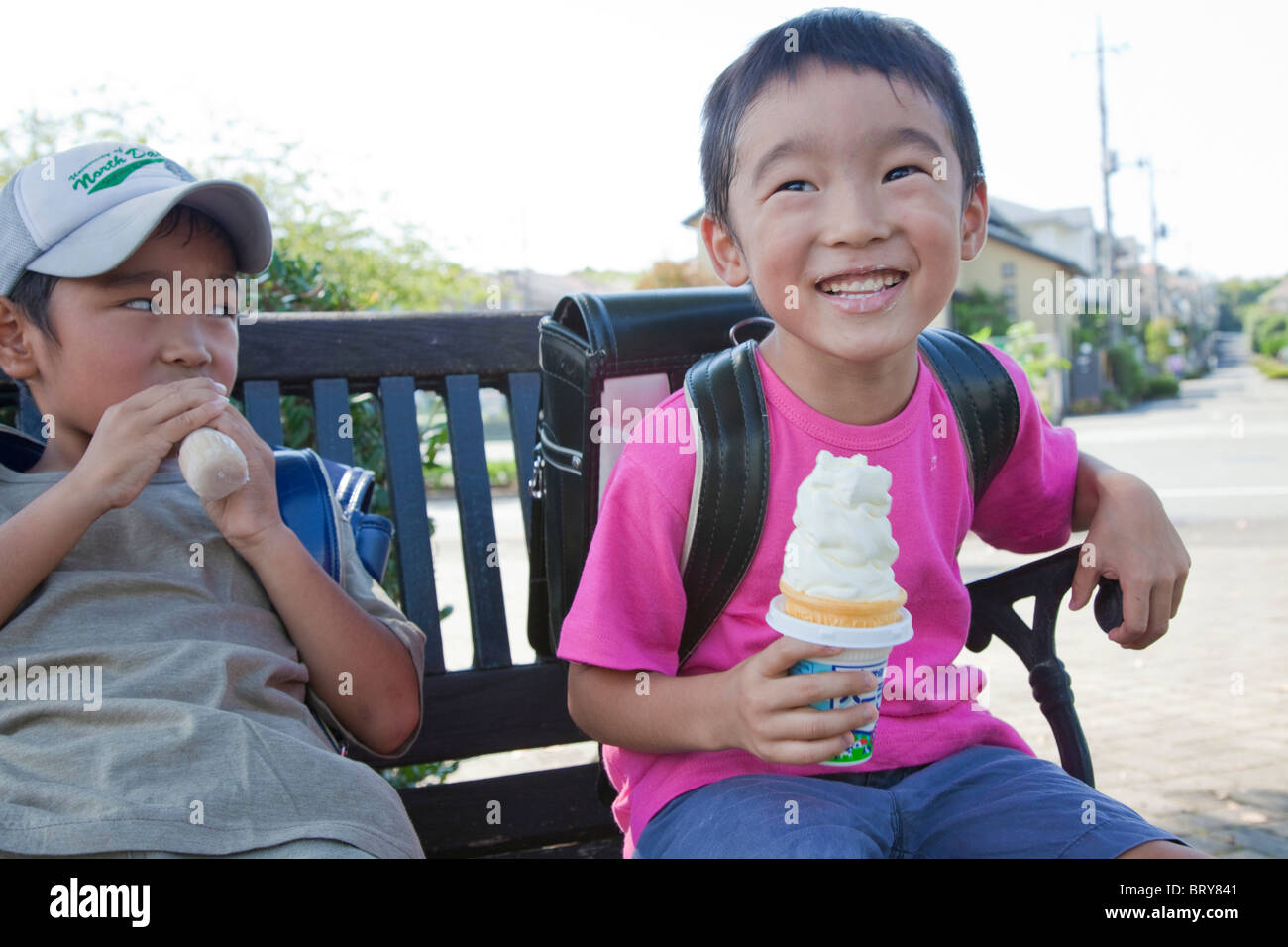 Boys sitting on bench eating ice cream, Japan Stock Photo - Alamy
