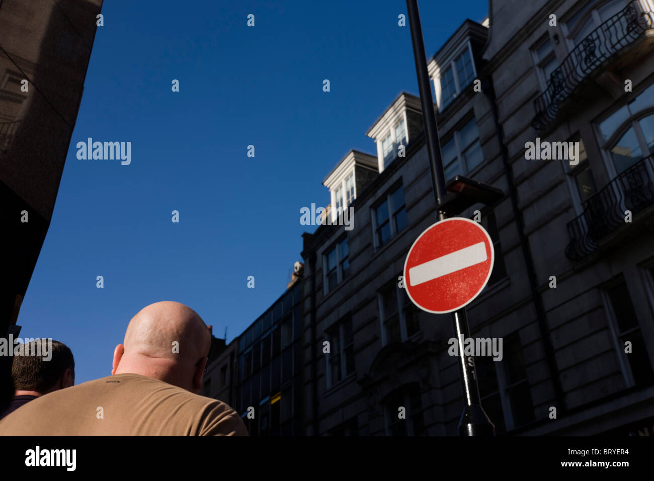 A bald-headed man walks below a no entry sign in central London Stock ...