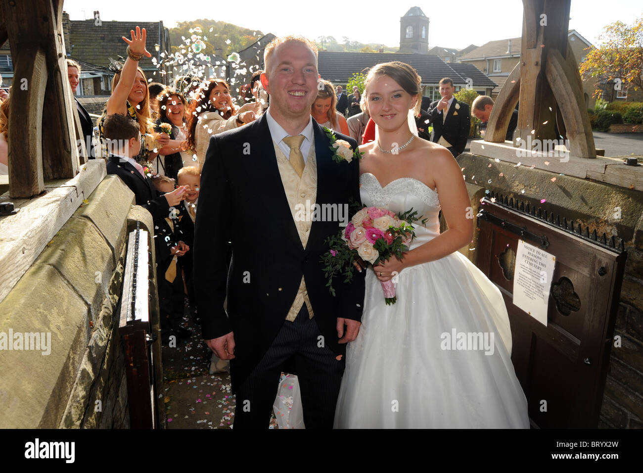 A young bride and groom have confetti thrown over them on their wedding ...