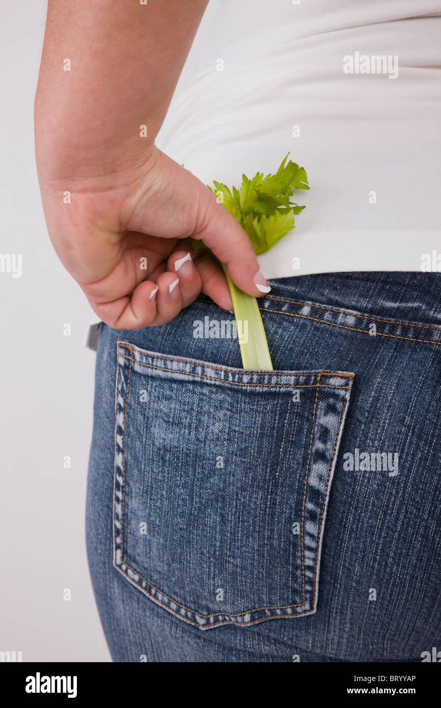 Overweight woman with celery in back jeans pocket, mid section, rear ...