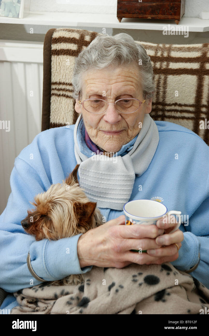 elderly woman keeping warm in winter wrapped up with rugs having a ...