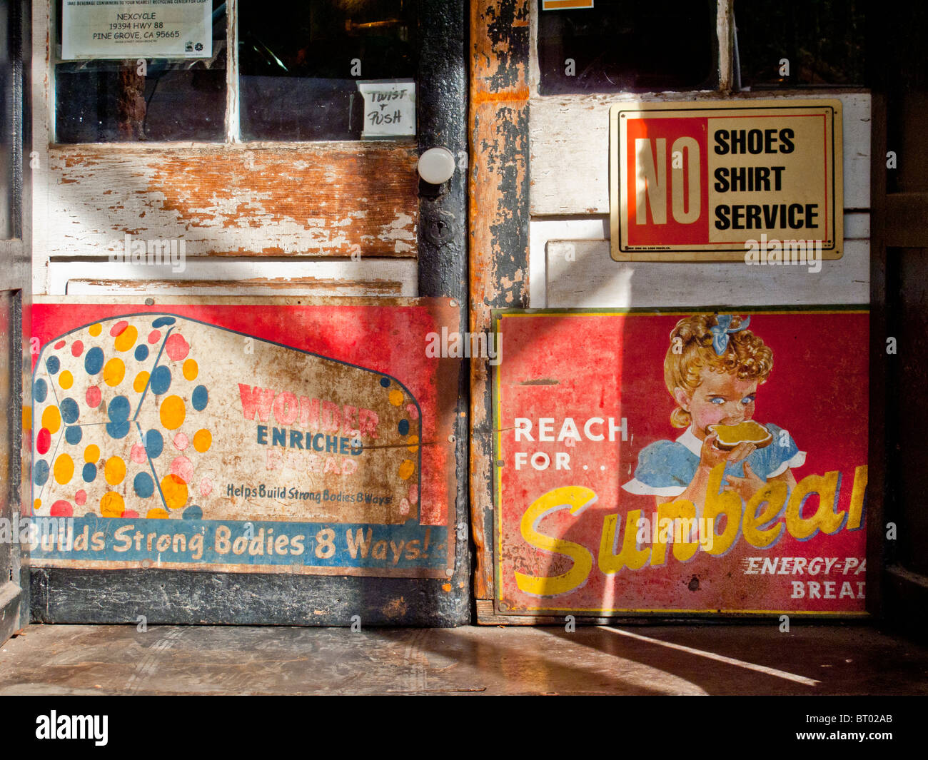 Faded bread advertising signs decorate the door of a grocery store in ...