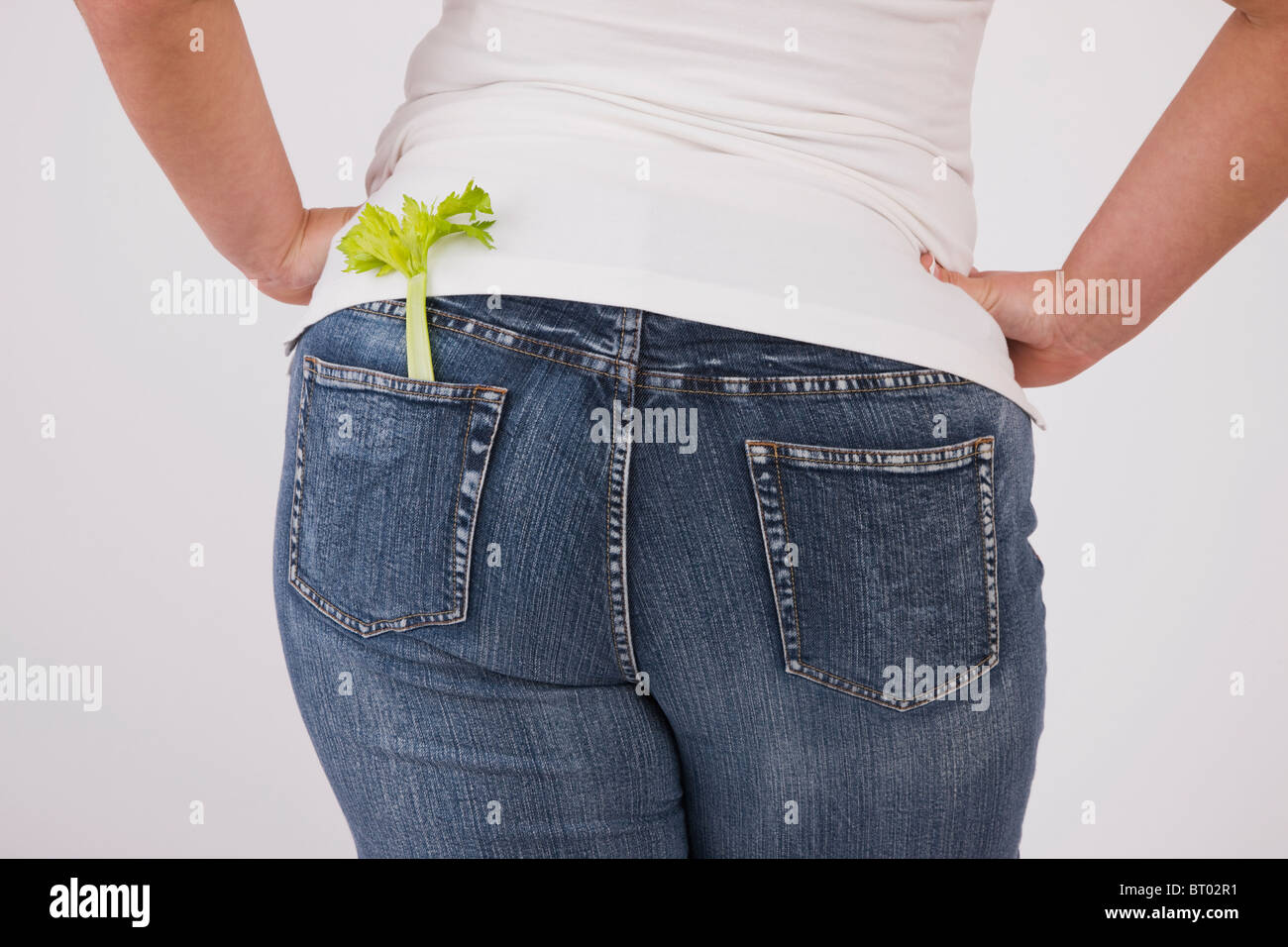 Overweight woman with celery in back jeans pocket, mid section, rear ...