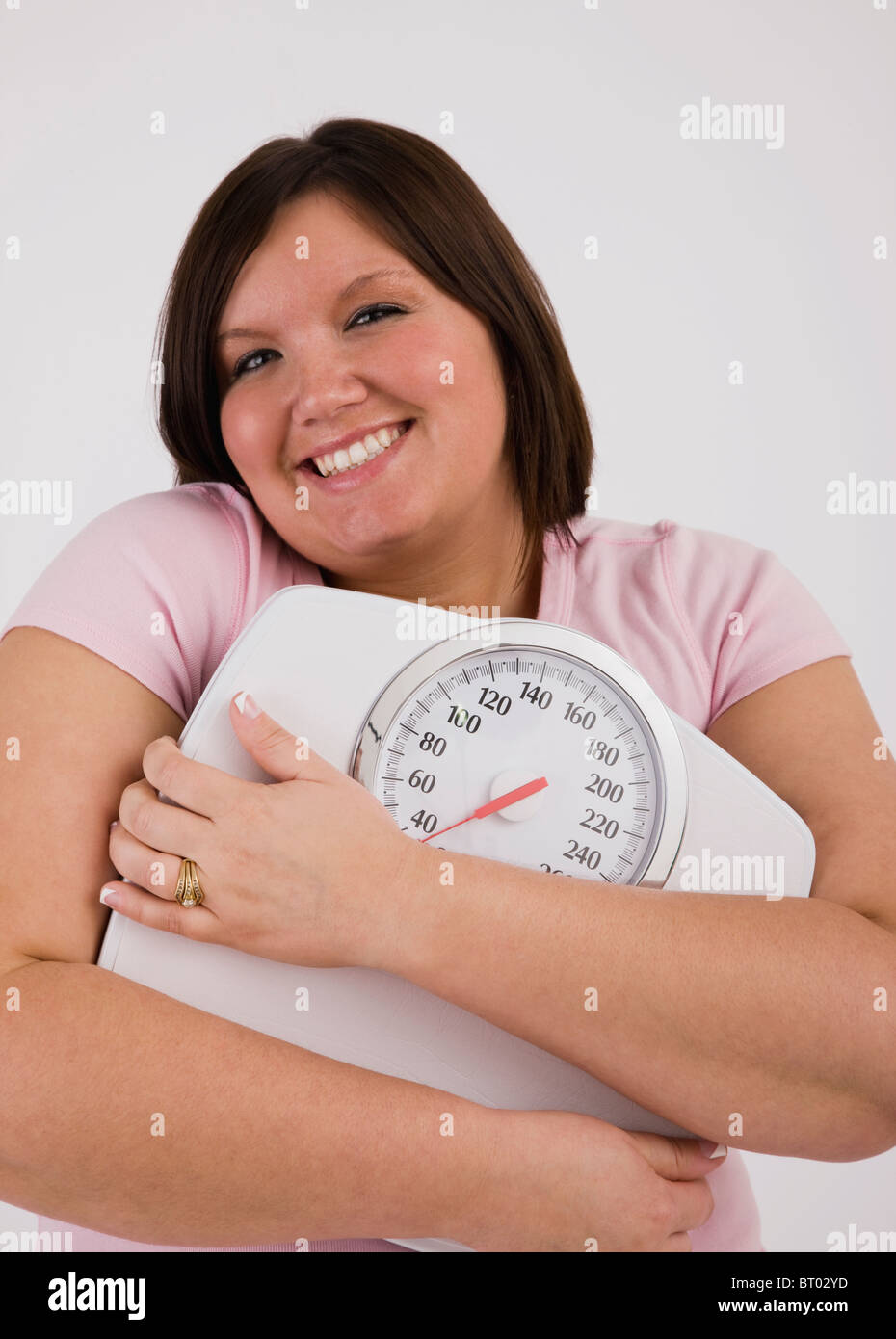 Portrait of young overweight woman hugging scales and smiling Stock ...