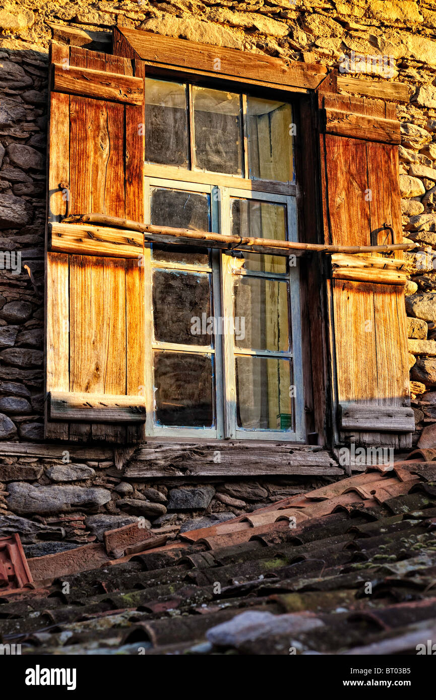 The shuttered window of a stone cottage in rural Turkey, lit by the ...