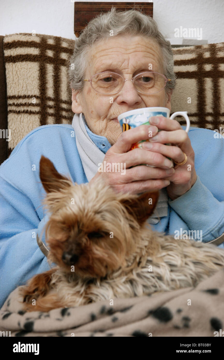 elderly woman keeping warm in winter wrapped up with rugs having a ...