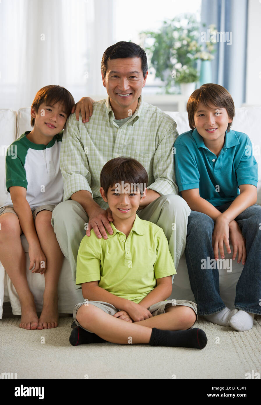 Smiling father and sons in living room Stock Photo - Alamy