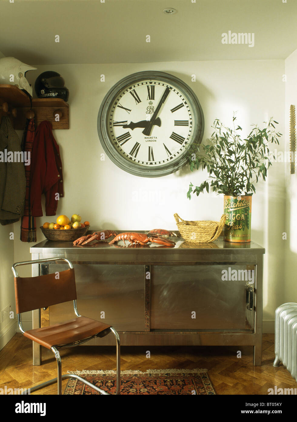 Large circular clock on wall above freestanding stainless steel unit in ...